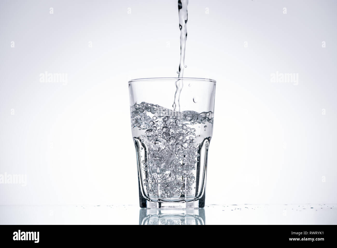 background of water pouring in glass on white with backlit and copy ...