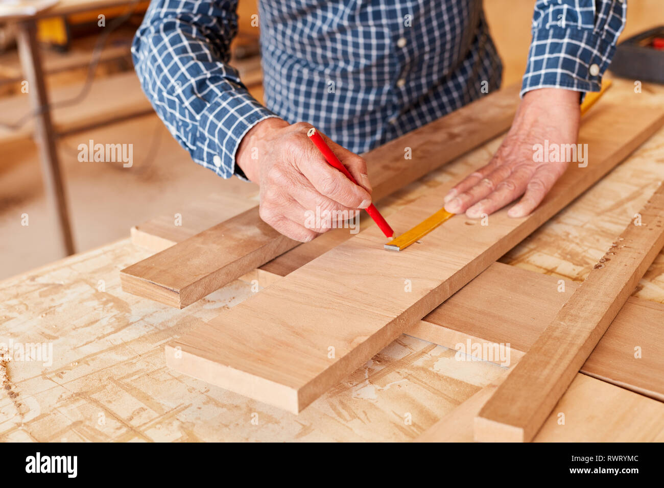 Carpenter hands with pencil and folding rule while measuring wood ...