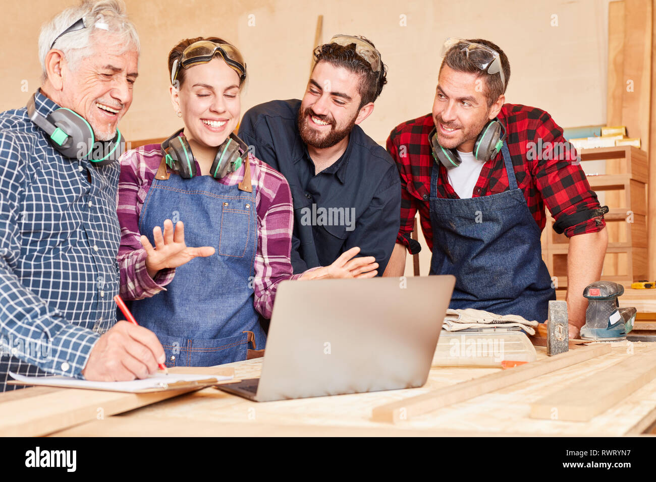 Apprentice and craftsman team at laptop computer are happy about an ...