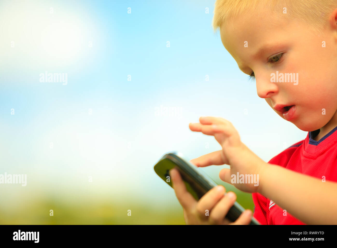 Little boy child kid playing games on smartphone mobile phone outdoor ...