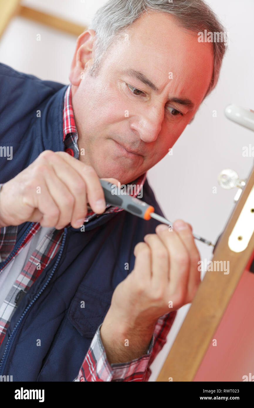 man fitting door lock using screwdriver Stock Photo - Alamy