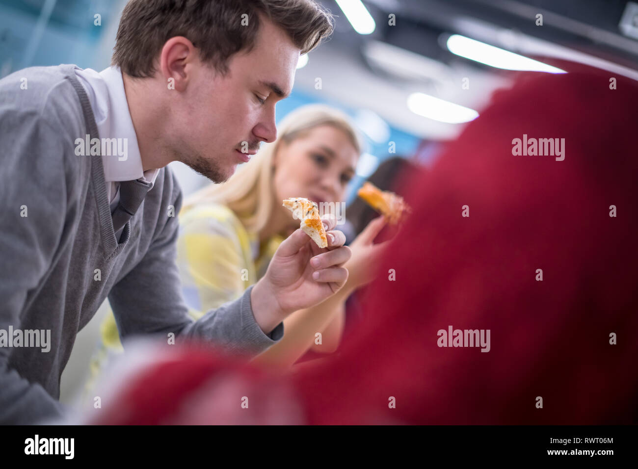 Friendly diverse multiethnic business team eating sharing pizza together in startup office ...