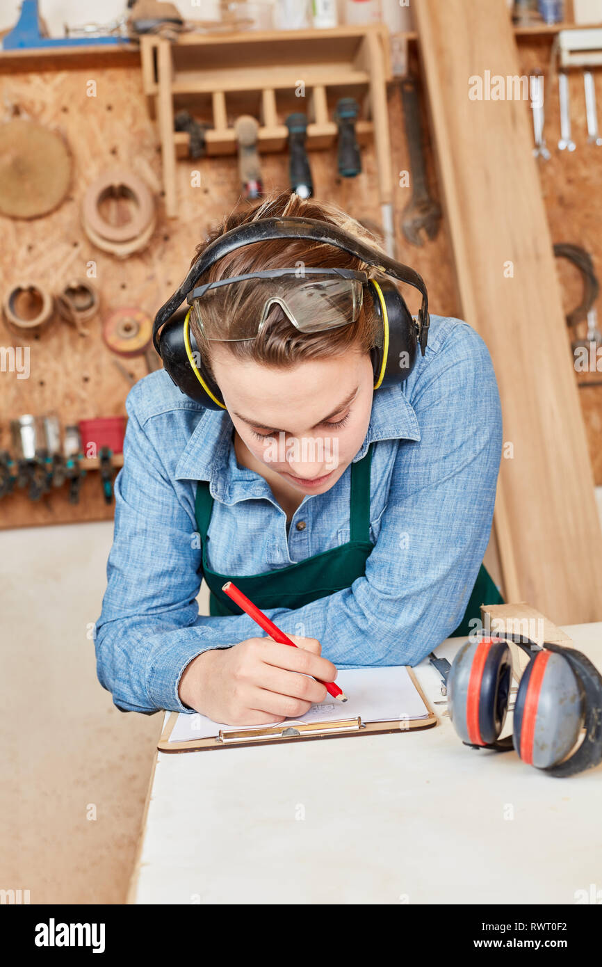 Young woman as a craftsman apprentice with checklist in a carpentry ...