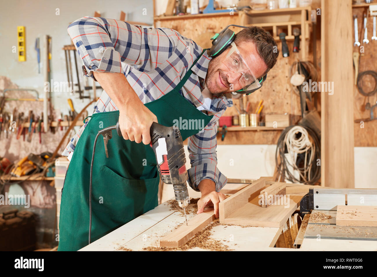 Man as a joiner in the apprenticeship works with the hand drill in the ...