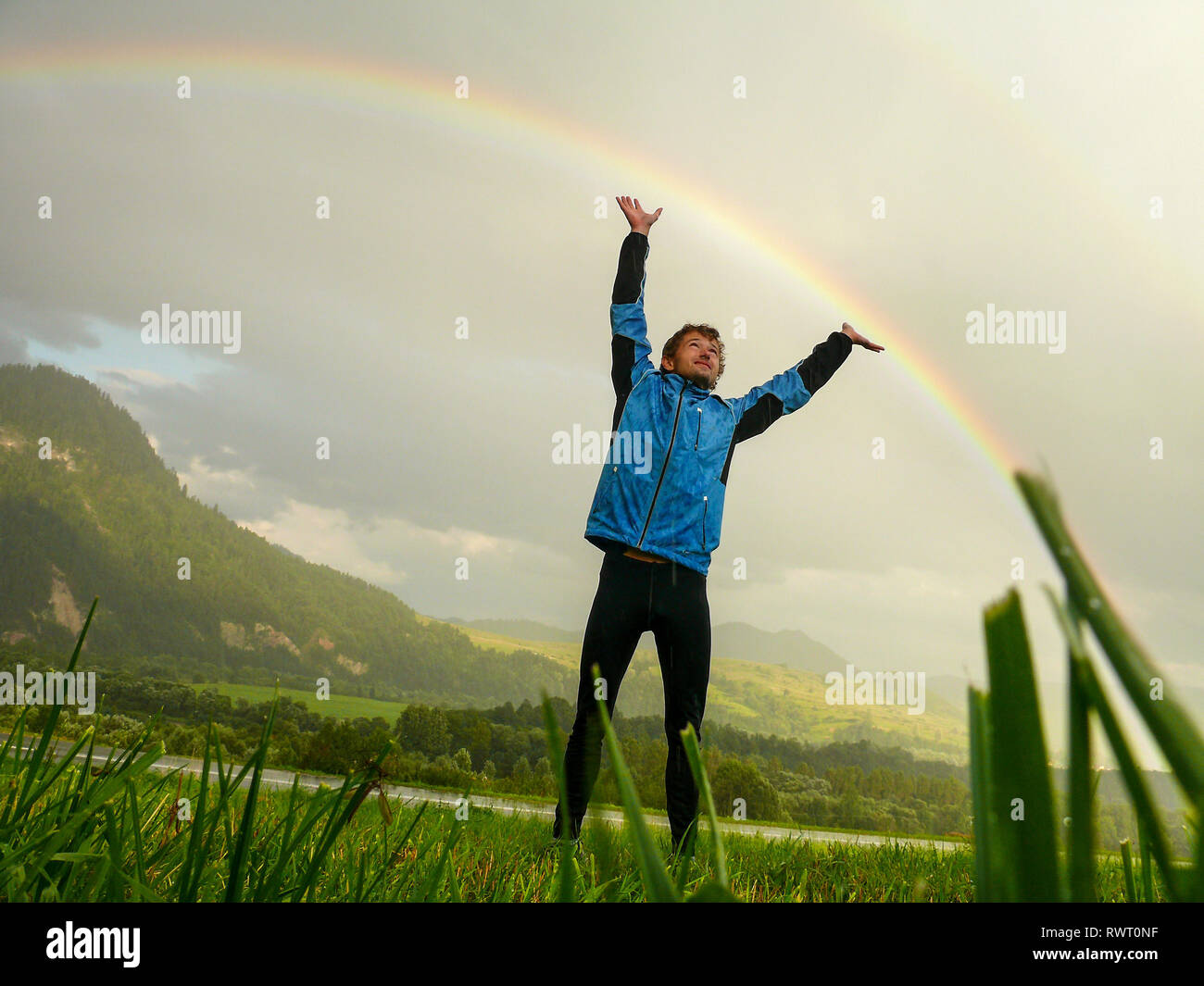 Touch a rainbow, Young man on colorful meadows holding a rainbow, Rainy ...