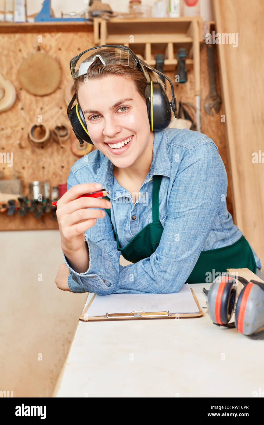 Smiling young woman as a craftsman apprentice with checklist in the ...