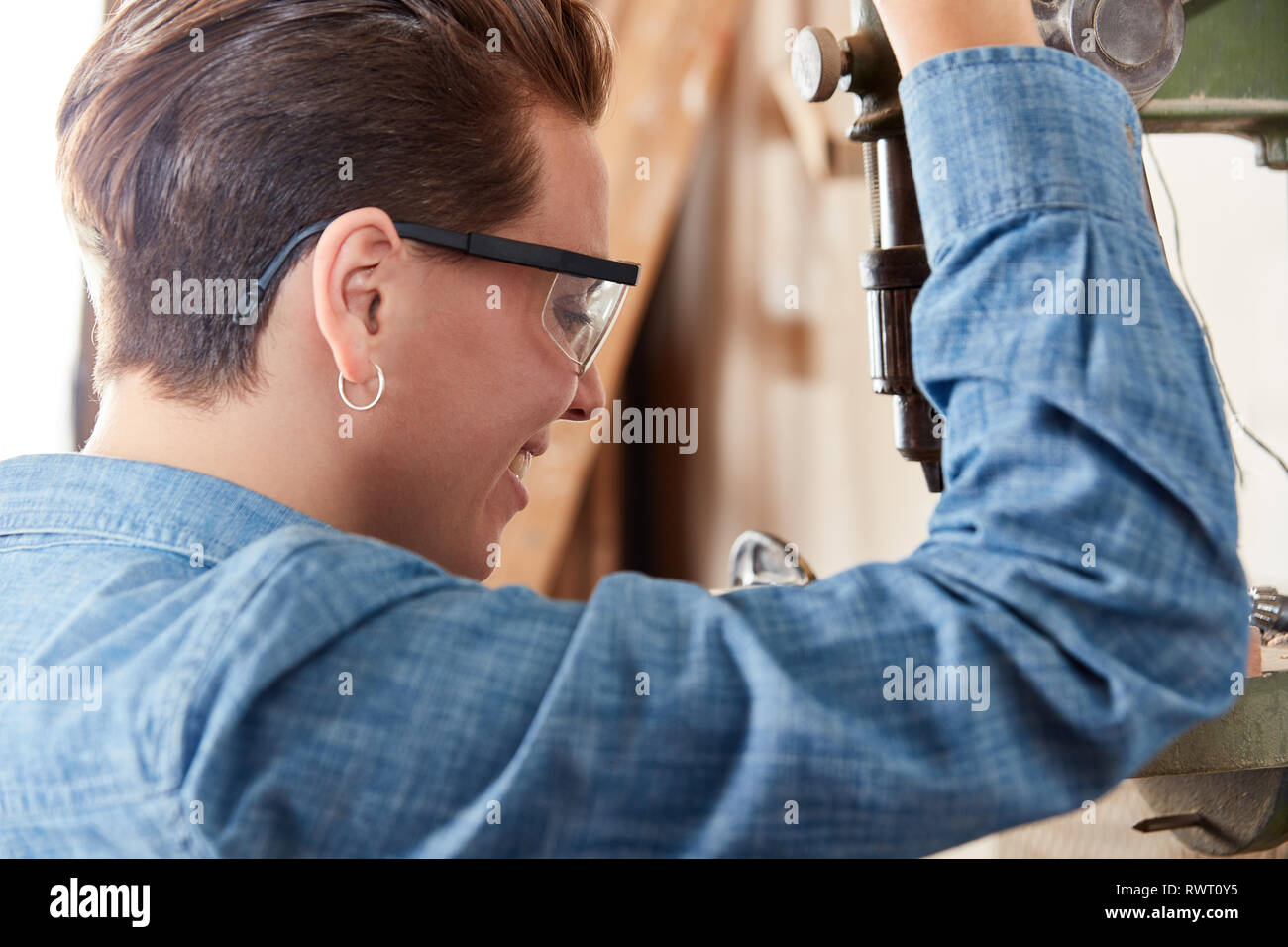 Young woman as a carpenter apprentice works on the drill in the ...