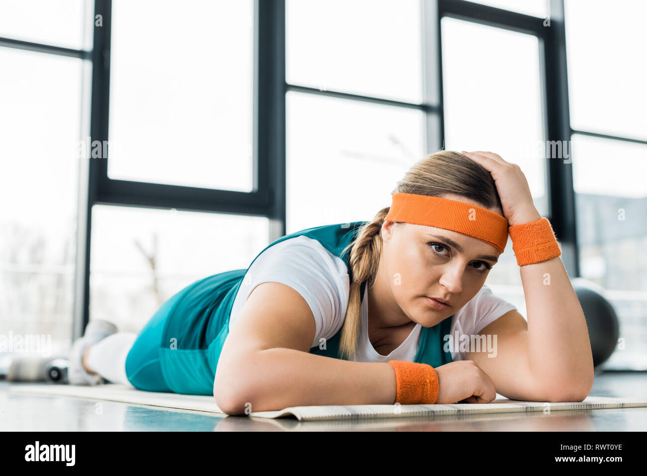 sad overweight girl lying on fitness mat in gym Stock Photo - Alamy