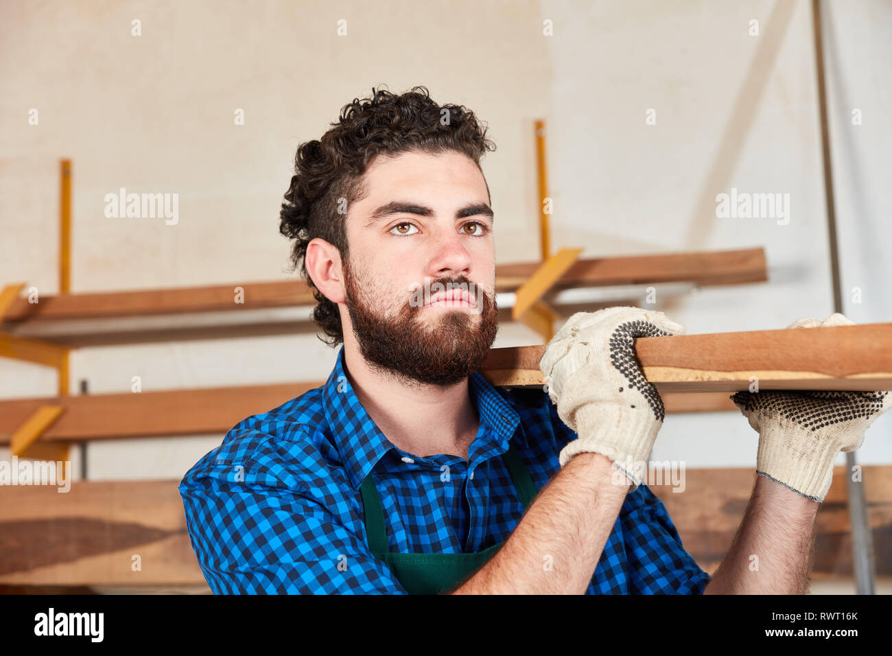 Man as a worker or joiner apprentice carries a joist in the joinery ...