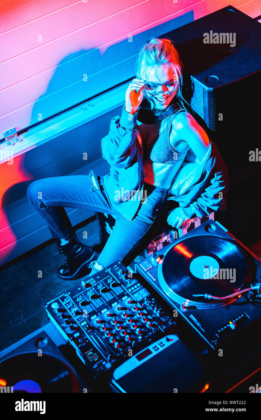 overhead view of cheerful dj woman touching glasses while sitting near ...
