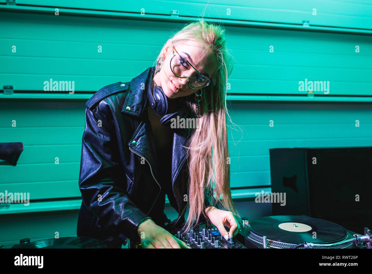 pretty blonde dj girl in glasses touching dj mixer in nightclub Stock ...