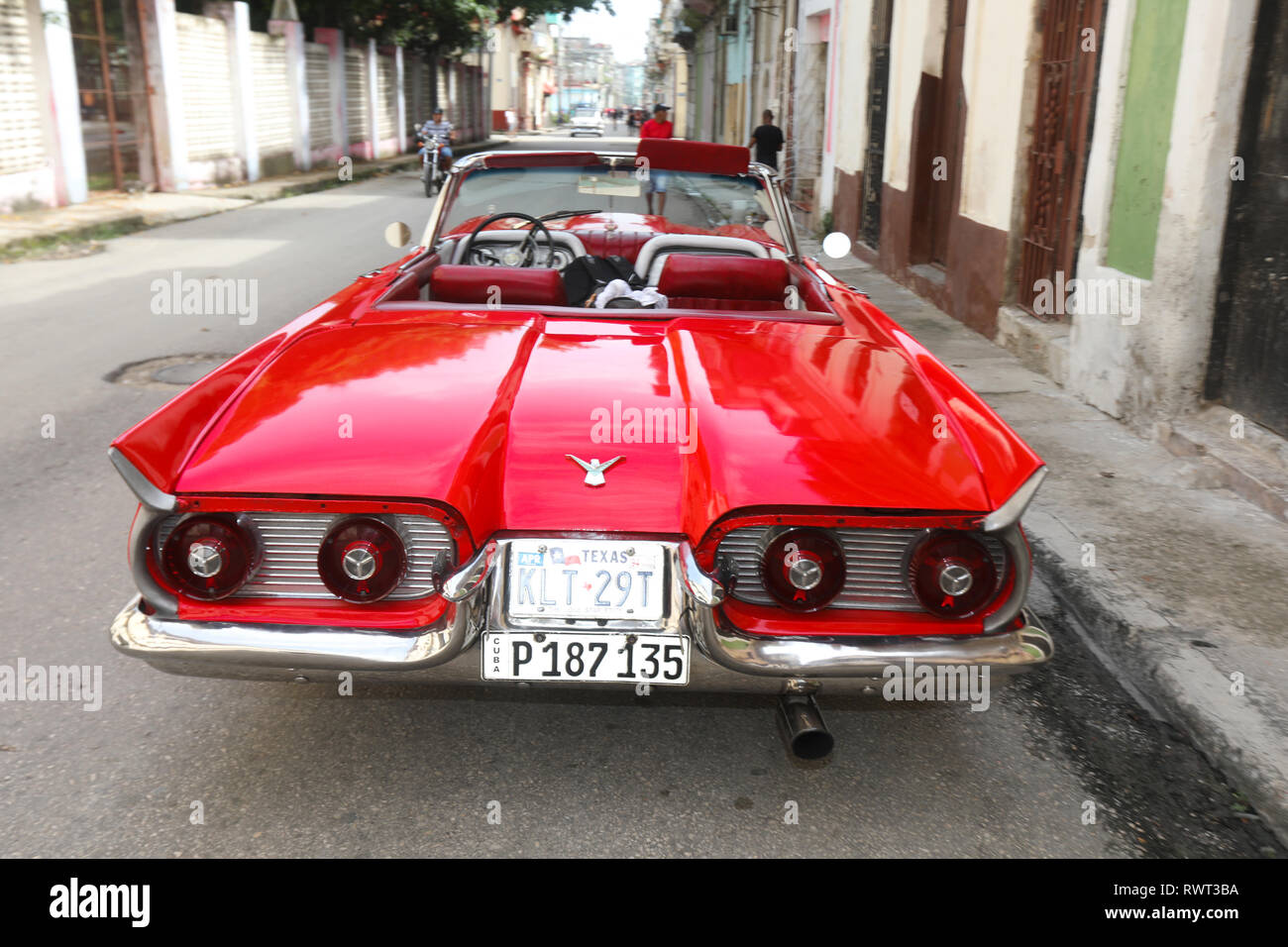 Classic red car driving among colonial buildings in the center of old ...