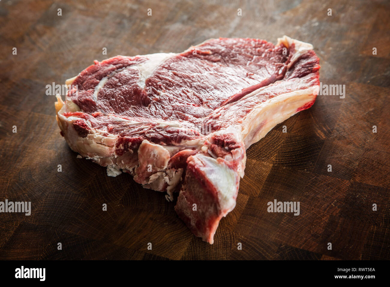 Rib eye steak with bone on butcher board Stock Photo - Alamy