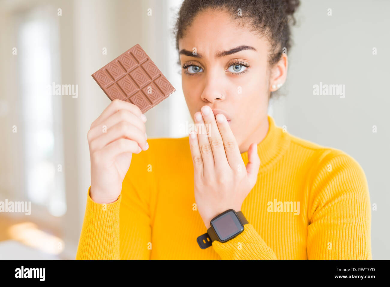 Young african american girl eating dark chocolate bar as a sweet snack ...