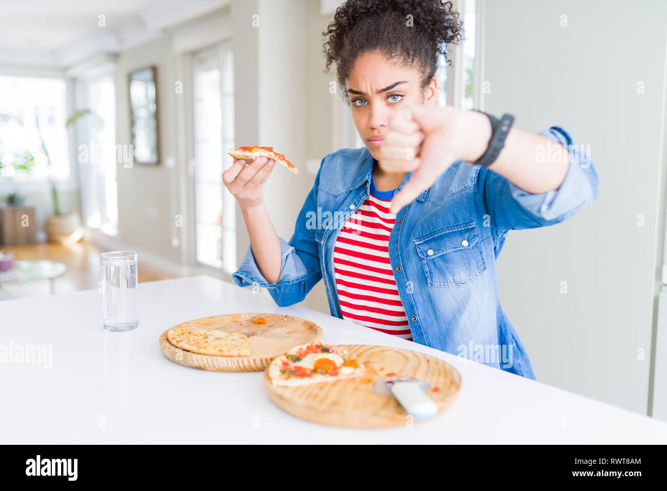 Young african american woman eating two homemade cheese pizzas with ...