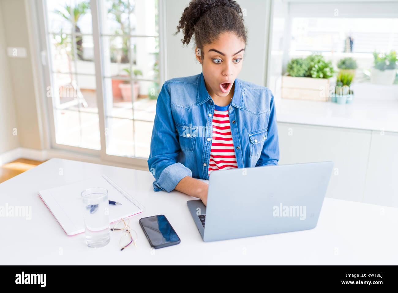 Young african american student woman using computer laptop scared in ...