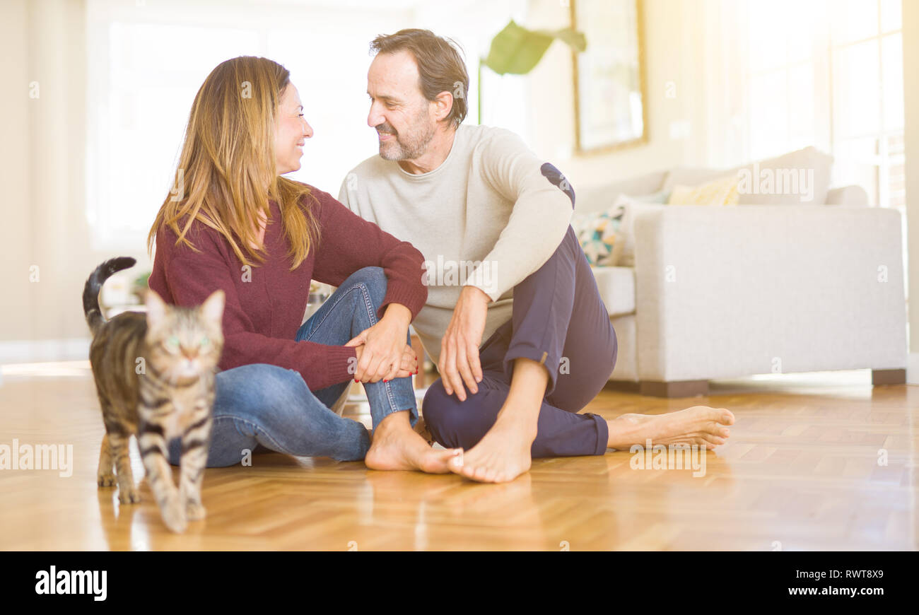 Beautiful romantic couple sitting together on the floor with the cat at ...