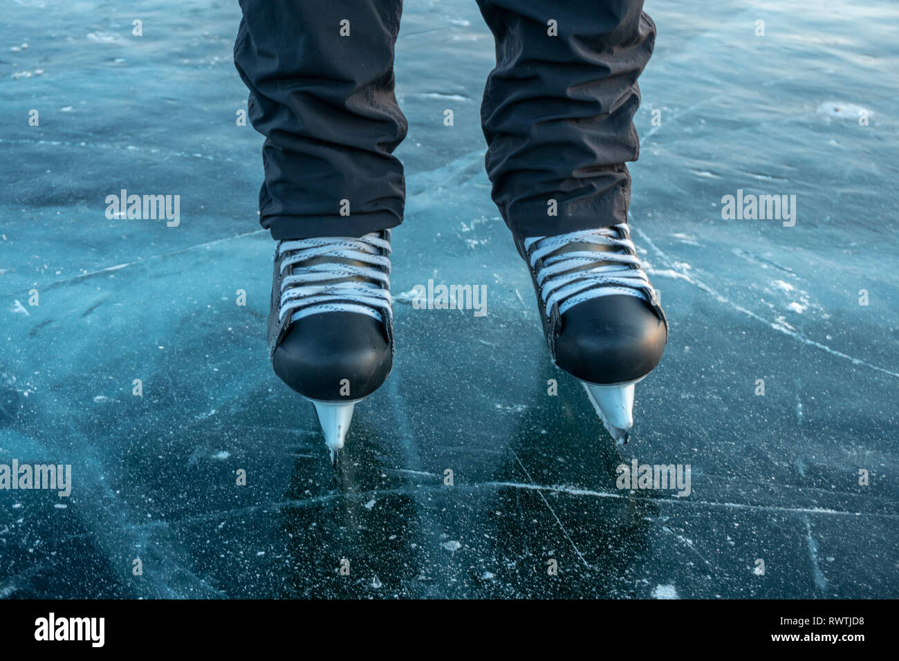 Men's feet skating on the clear ice of lake Baikal. Ice skating in ...