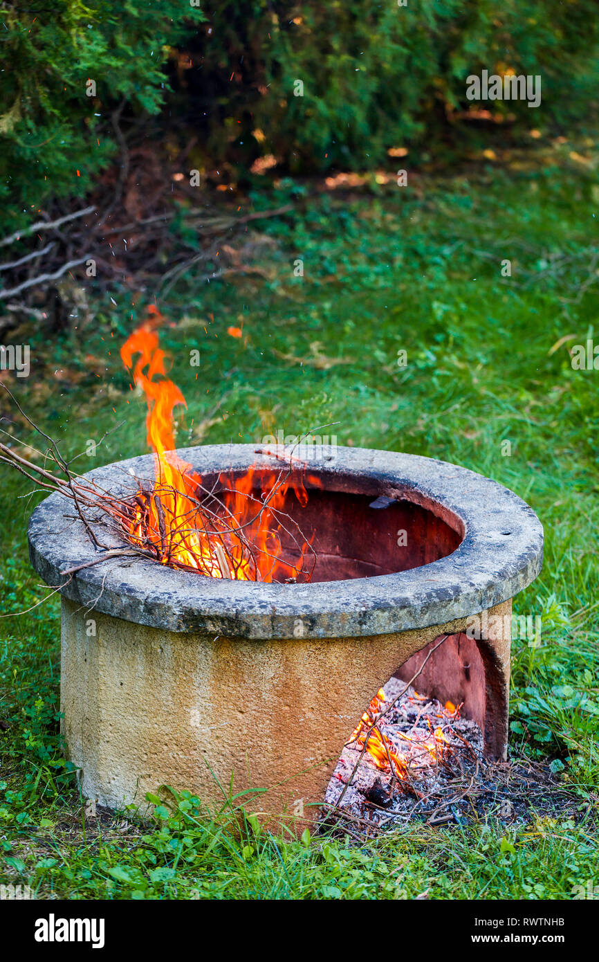 Dry branches burn in isolated campfire pit in the garden. High bright ...