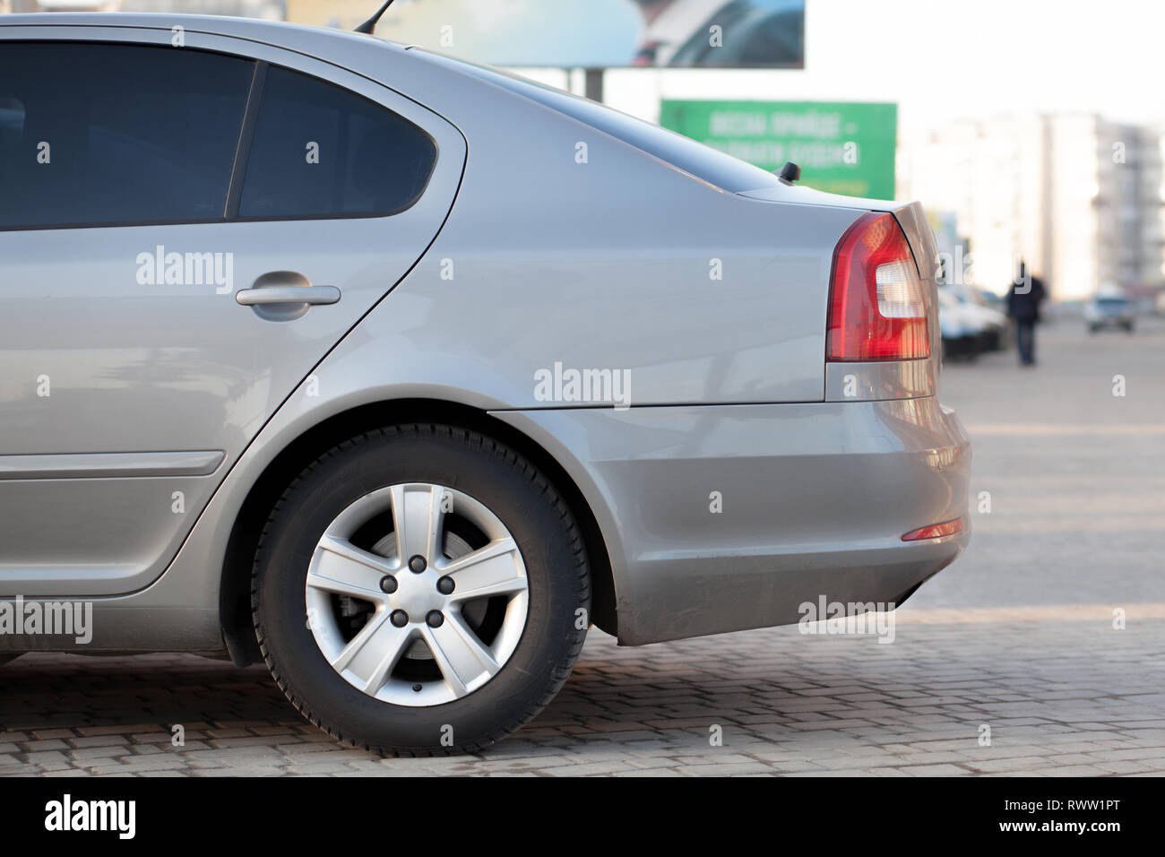 Side view of silver car parked in paved parking lot area on blurred ...