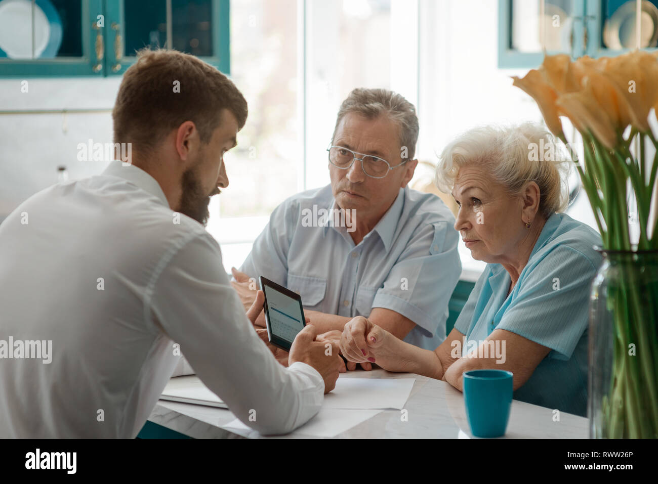 Businessman talks with elderly parents, discussing something serious ...