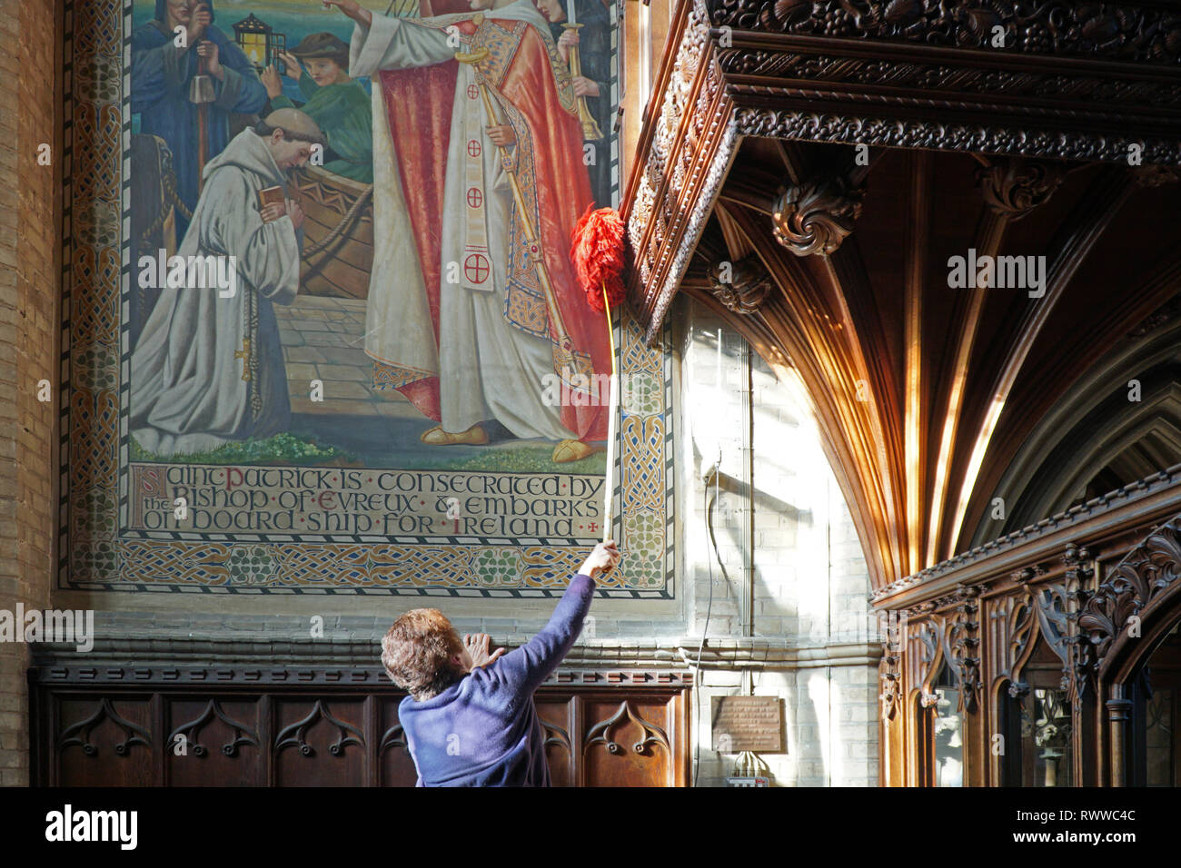Woman cleaning inside a church using a feather duster to remove dust ...