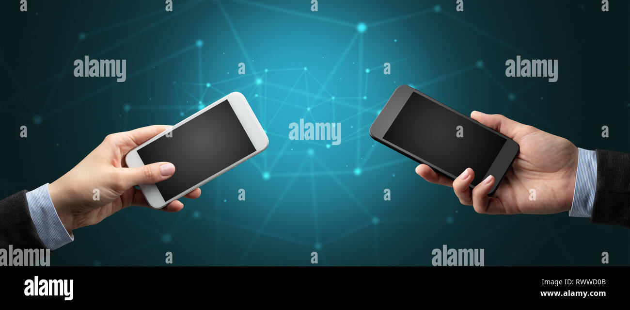 Close up of two hands holding smartphones to each other, wireless ...