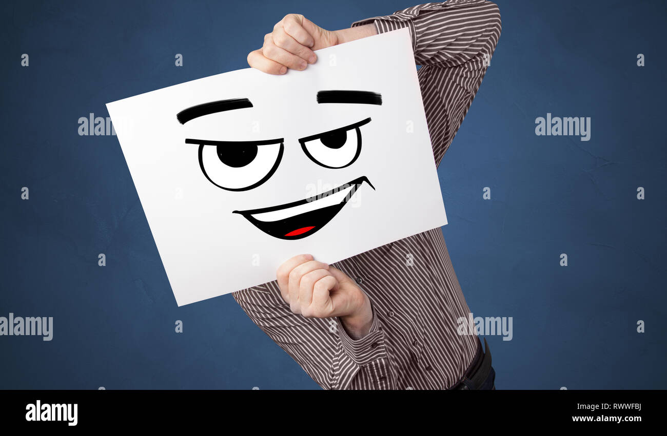 Casual person holding a paper in front of his face with drawn emoticon ...