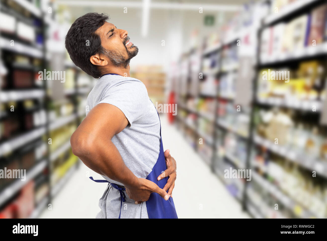 Indian male supermarket or hypermarket worker with hurting expression ...