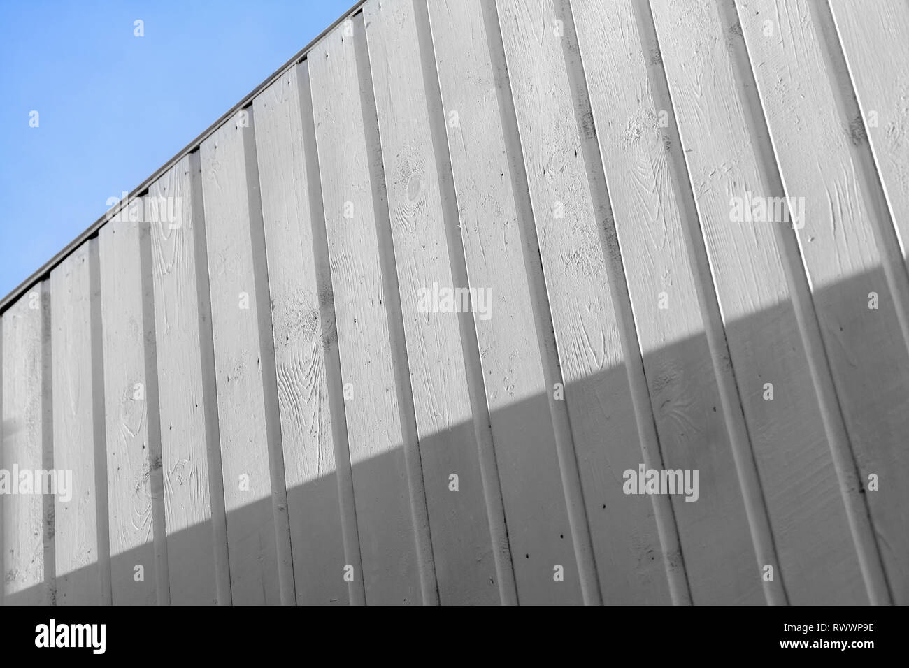 White wooden wall with shadow area under blue sky, abstract vertical ...