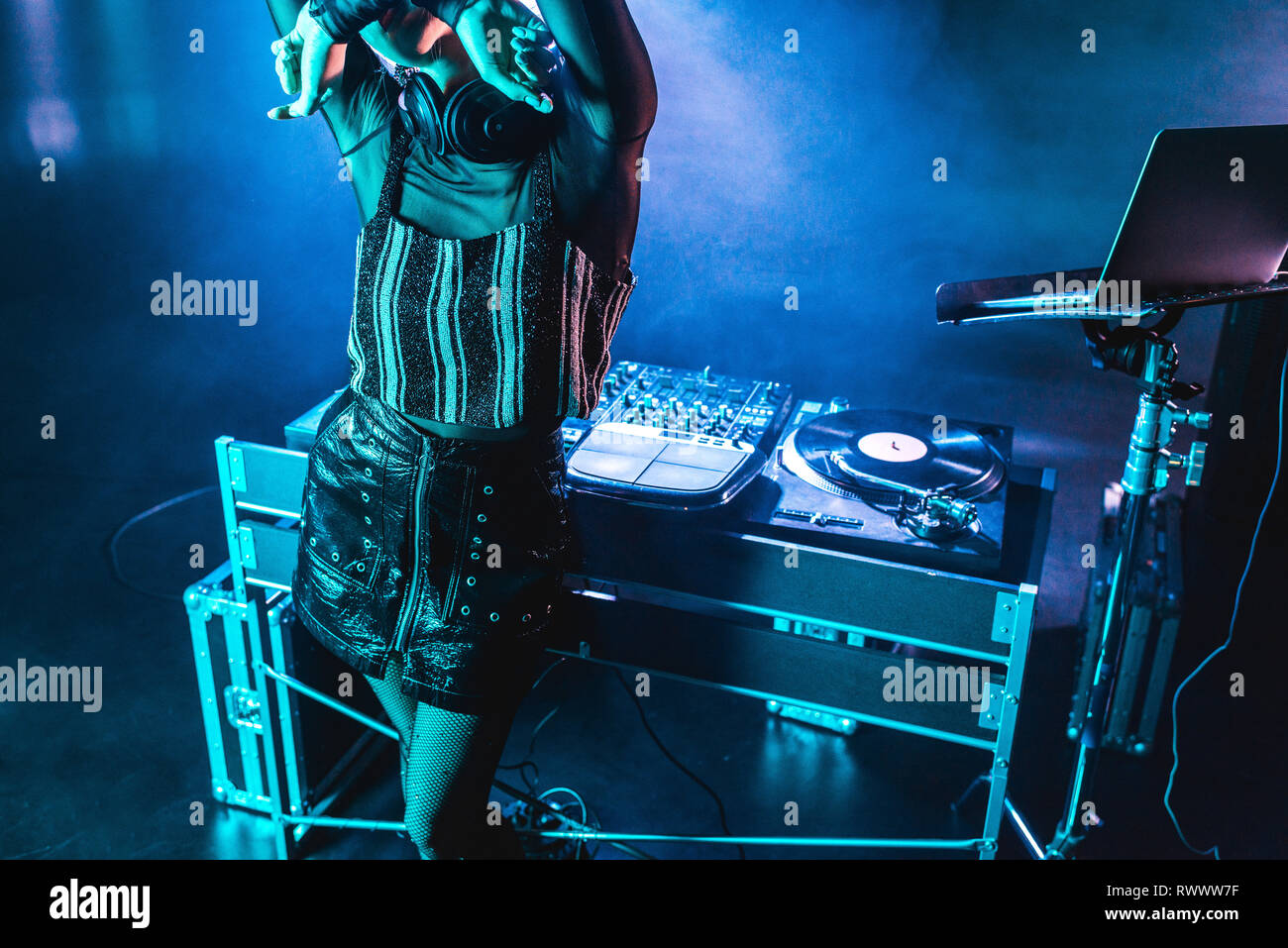 dj woman covering face while standing near dj equipment in nightclub ...