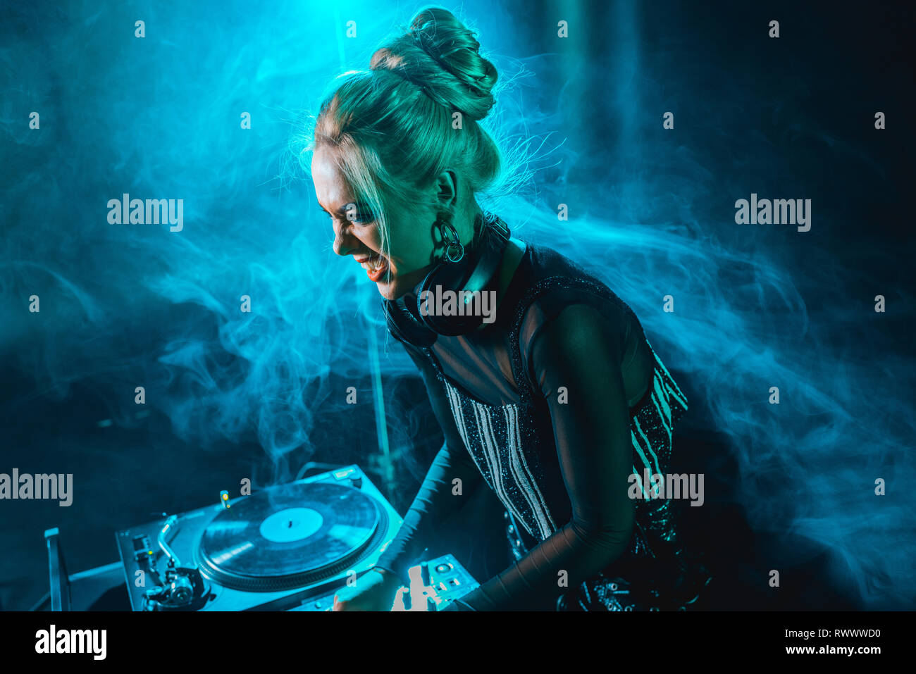 angry blonde dj girl using dj equipment in nightclub with smoke Stock ...