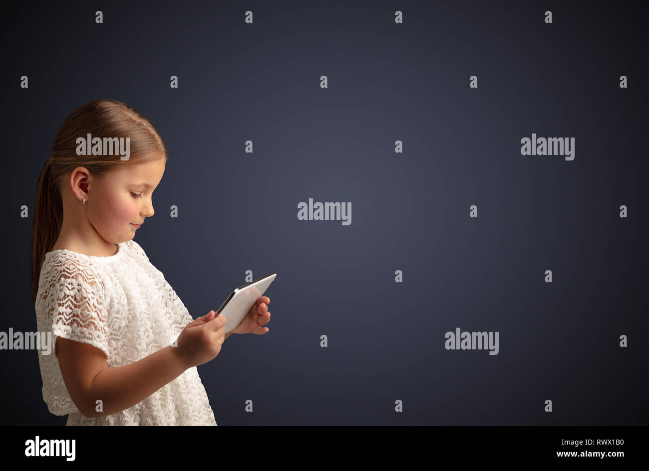 Adorable little girl using tablet with dark empty space Stock Photo - Alamy