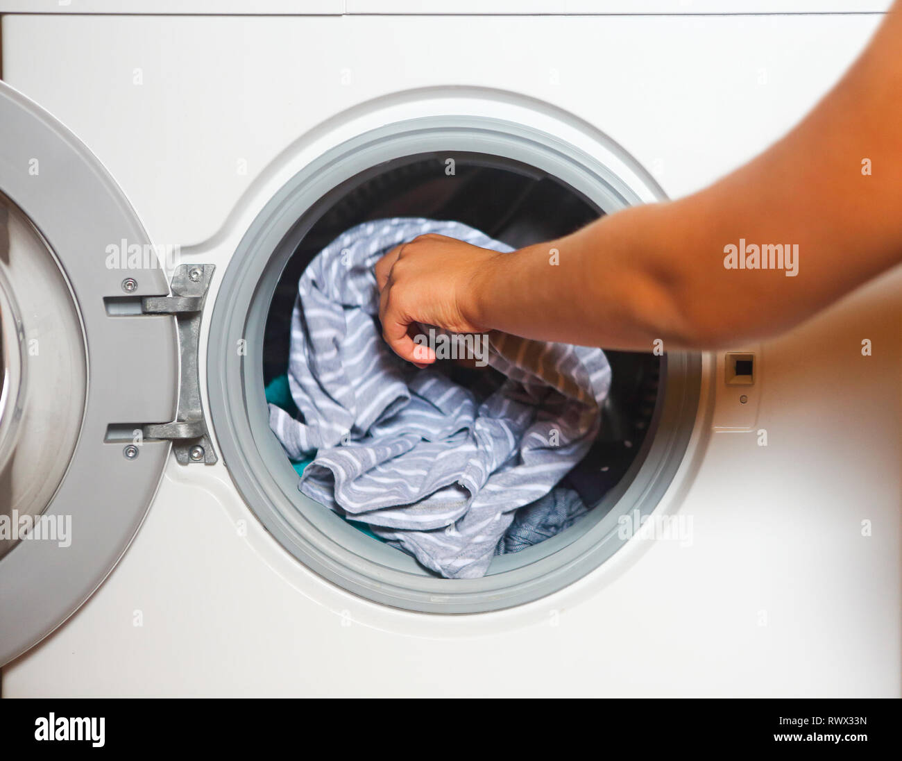 Cropped shot of young woman taking laundry from washing machine Stock ...
