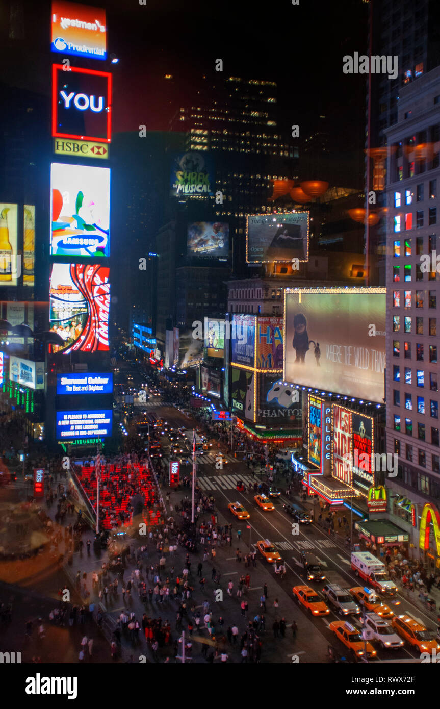 Bright neon signage flashes over crowds and taxi traffic zooming past ...