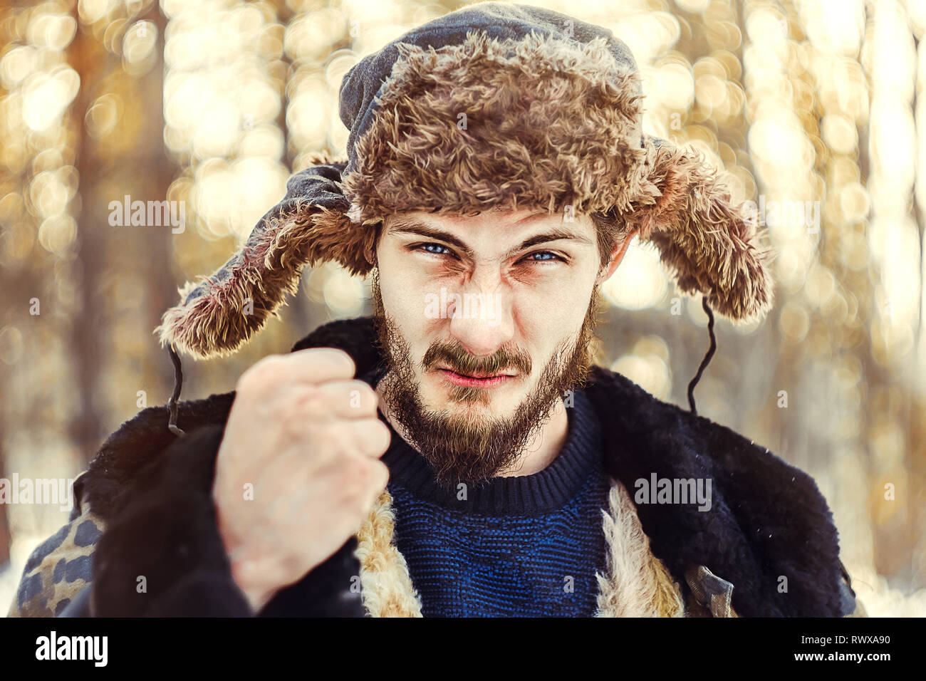 angry man in hat with earflaps shows fist Stock Photo - Alamy