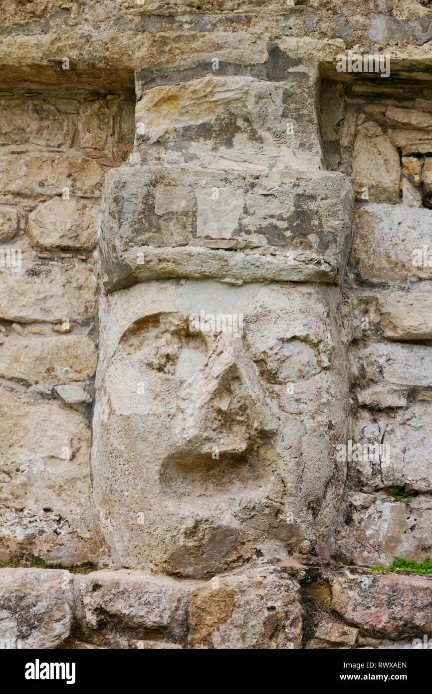 Close up of a weathered Mayan carved head set in to a wall in Palenque ...