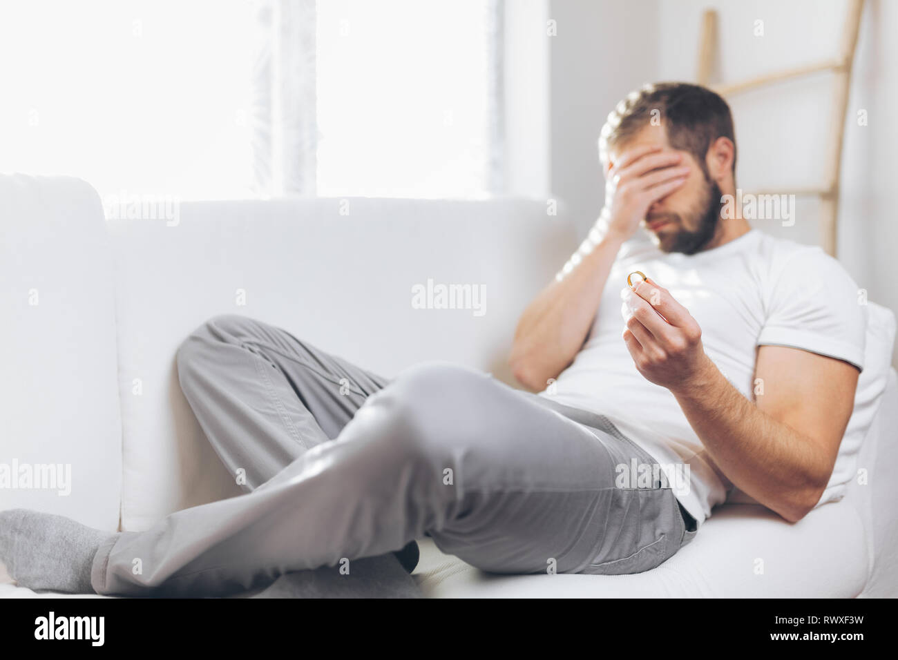 Heartbroken man at home holding a wedding ring Stock Photo - Alamy