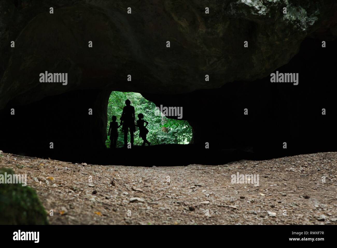 Mother with two daughters in dark stone age cave. Silhouettes only are ...