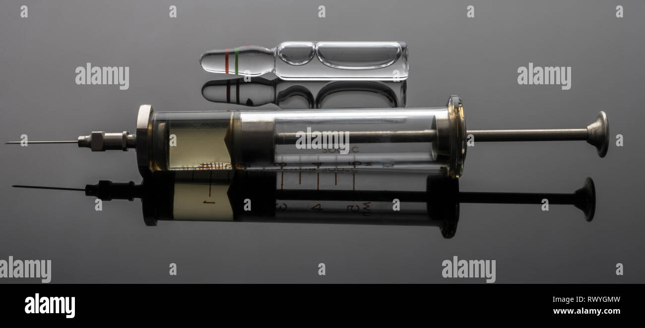 Vintage syringe next to vials with medication, conceptual image ...