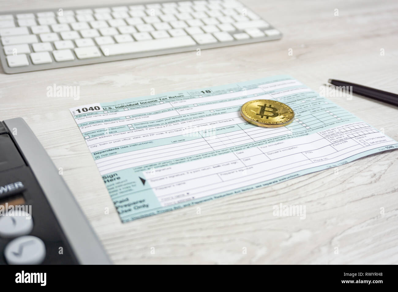 The pen, bitcoins and calculator on the tax form 1040 U.S. Individual ...