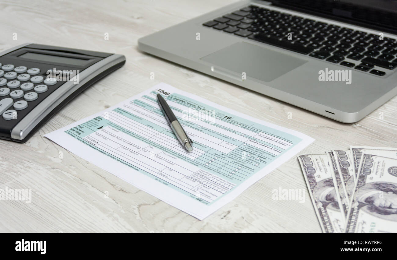 US tax form next to computer laptop, dollar bills, calculator and tax ...