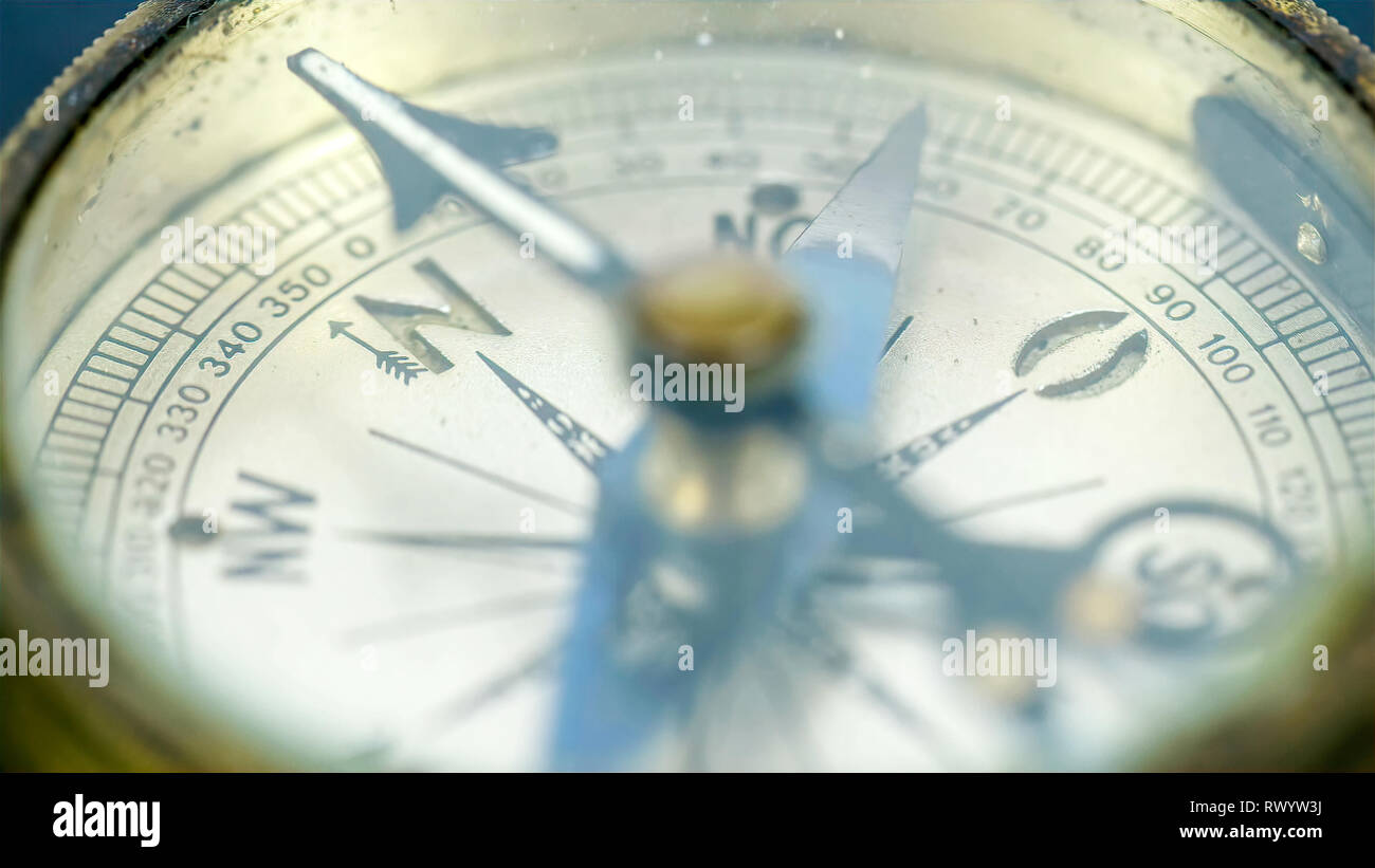 An old small round compass on a table. This old ancient compass is used ...