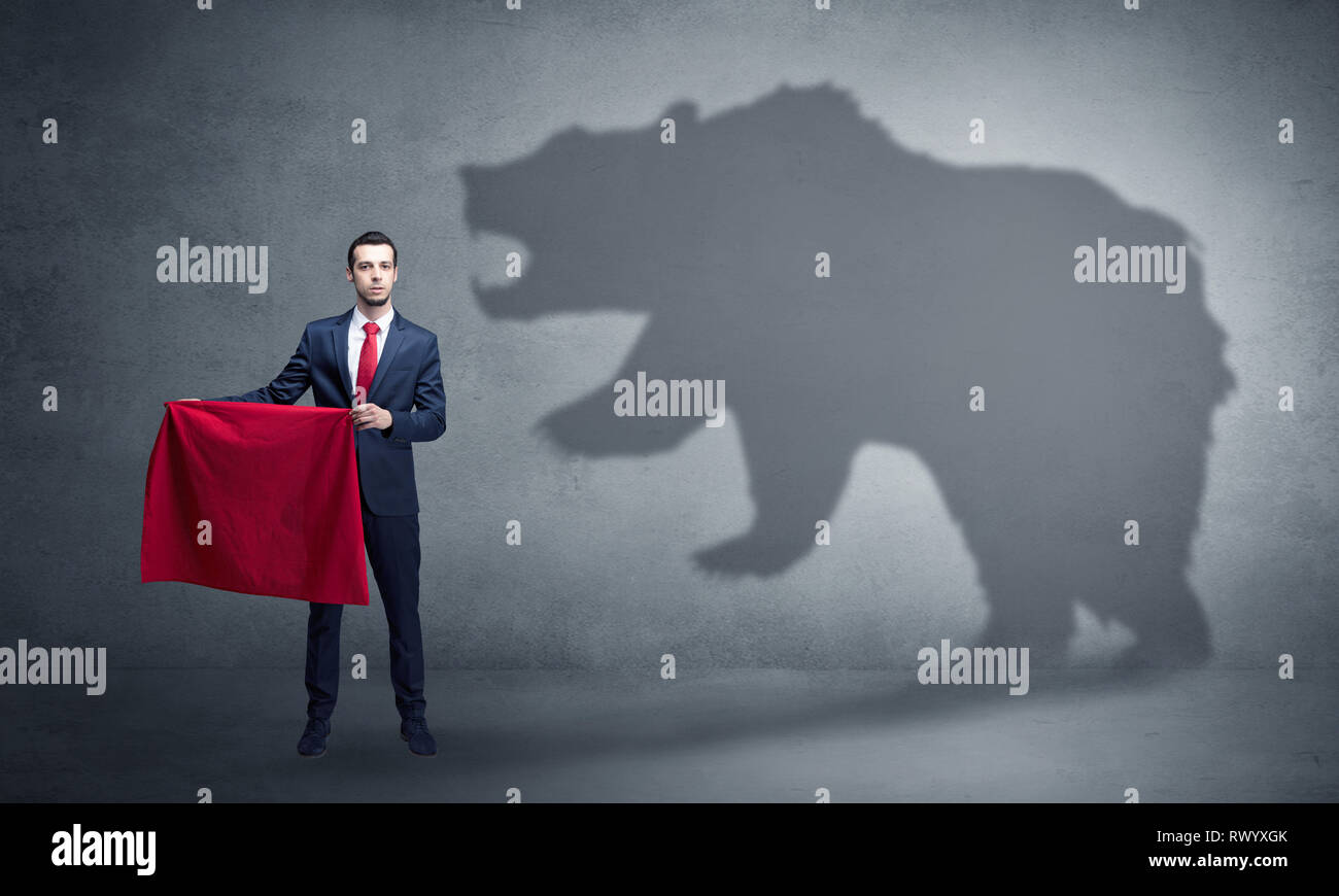 Businessman standing with red cloth in his hand and big bear shadow on ...