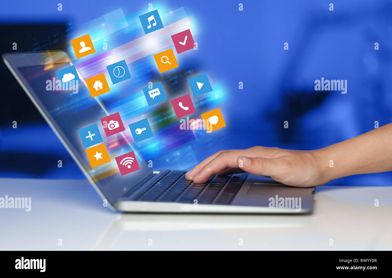 Hand using laptop with colorful fast moving application icons and ...