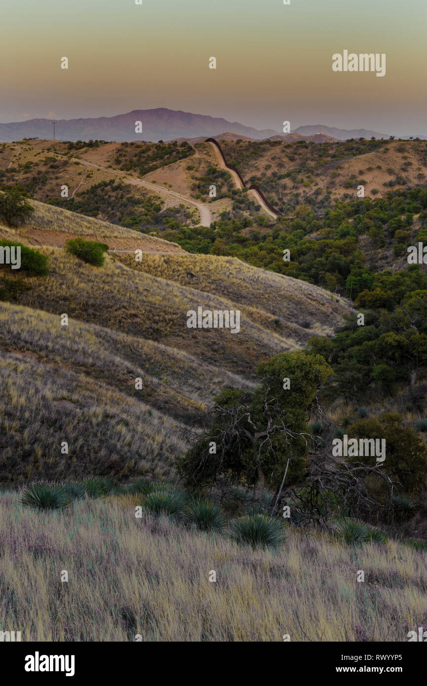 US Border Fence across rolling hills at dusk, looking south from just ...