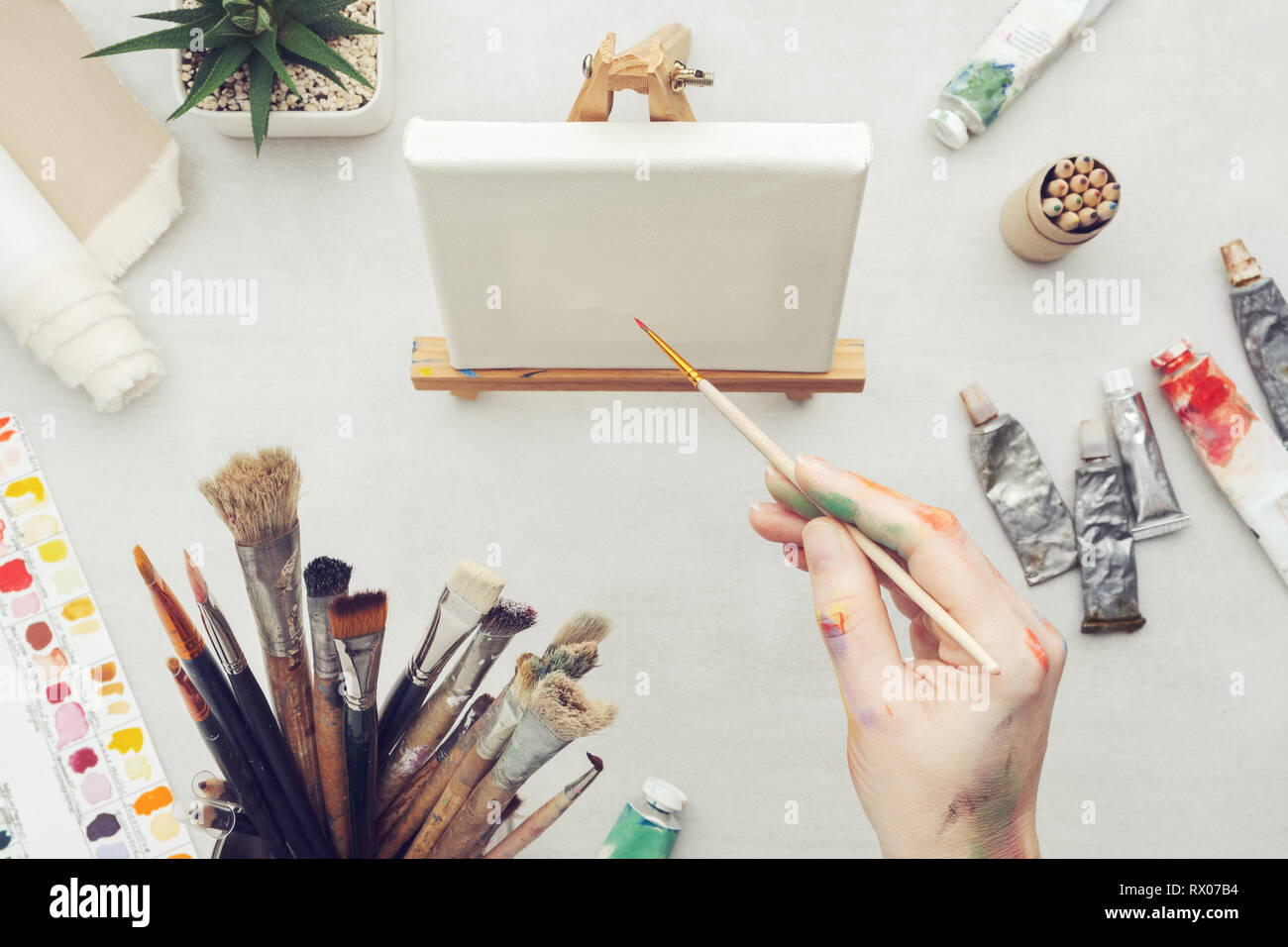 Painter holding a paintbrush in his hand. Canvas on the easel and ...