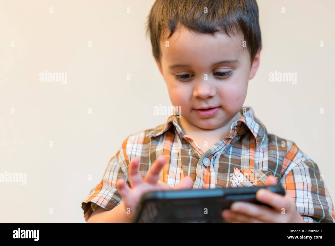 Portrait of a smiling little boy holding mobile phone isolated over ...