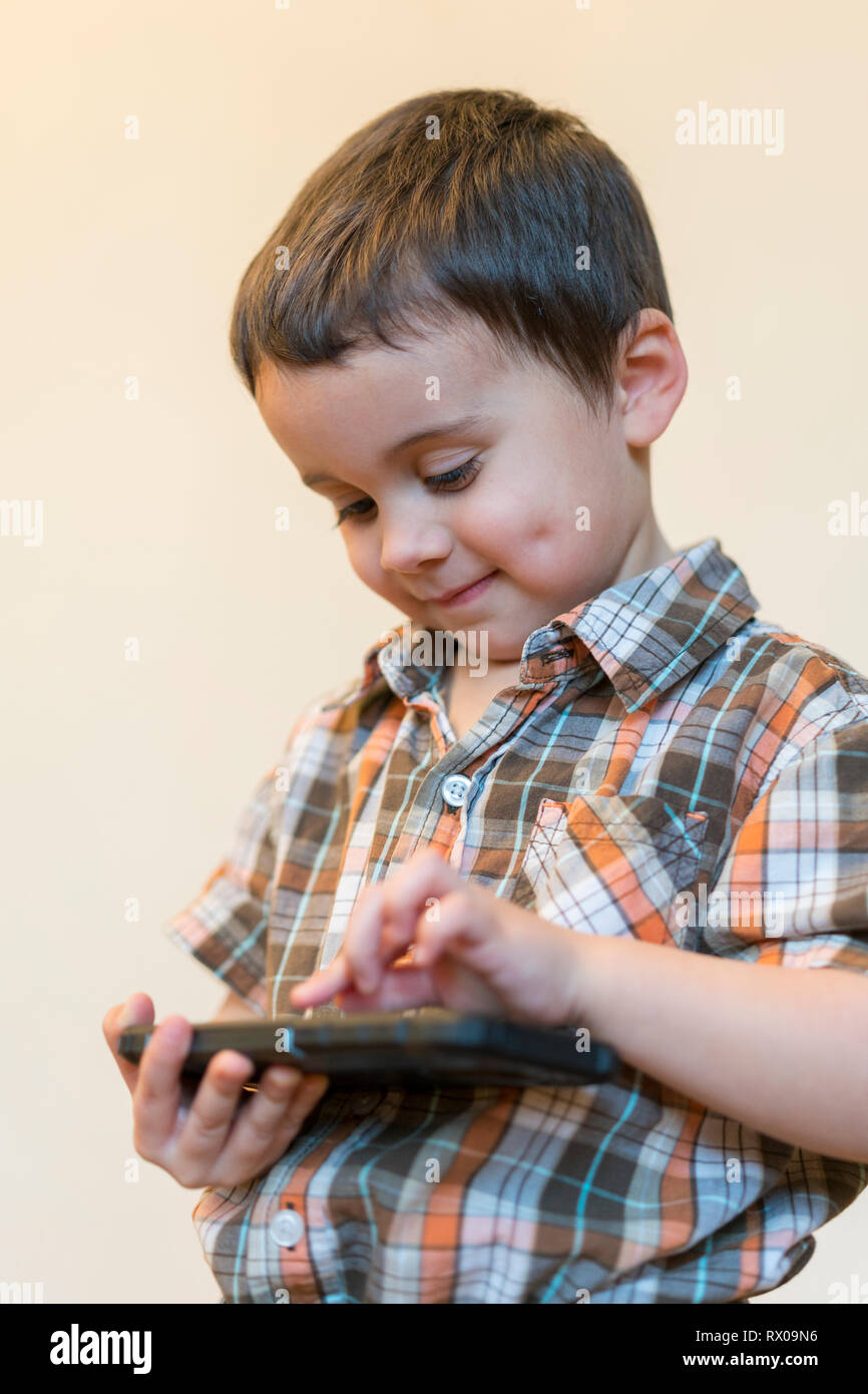 Portrait of a smiling little boy holding mobile phone isolated over ...
