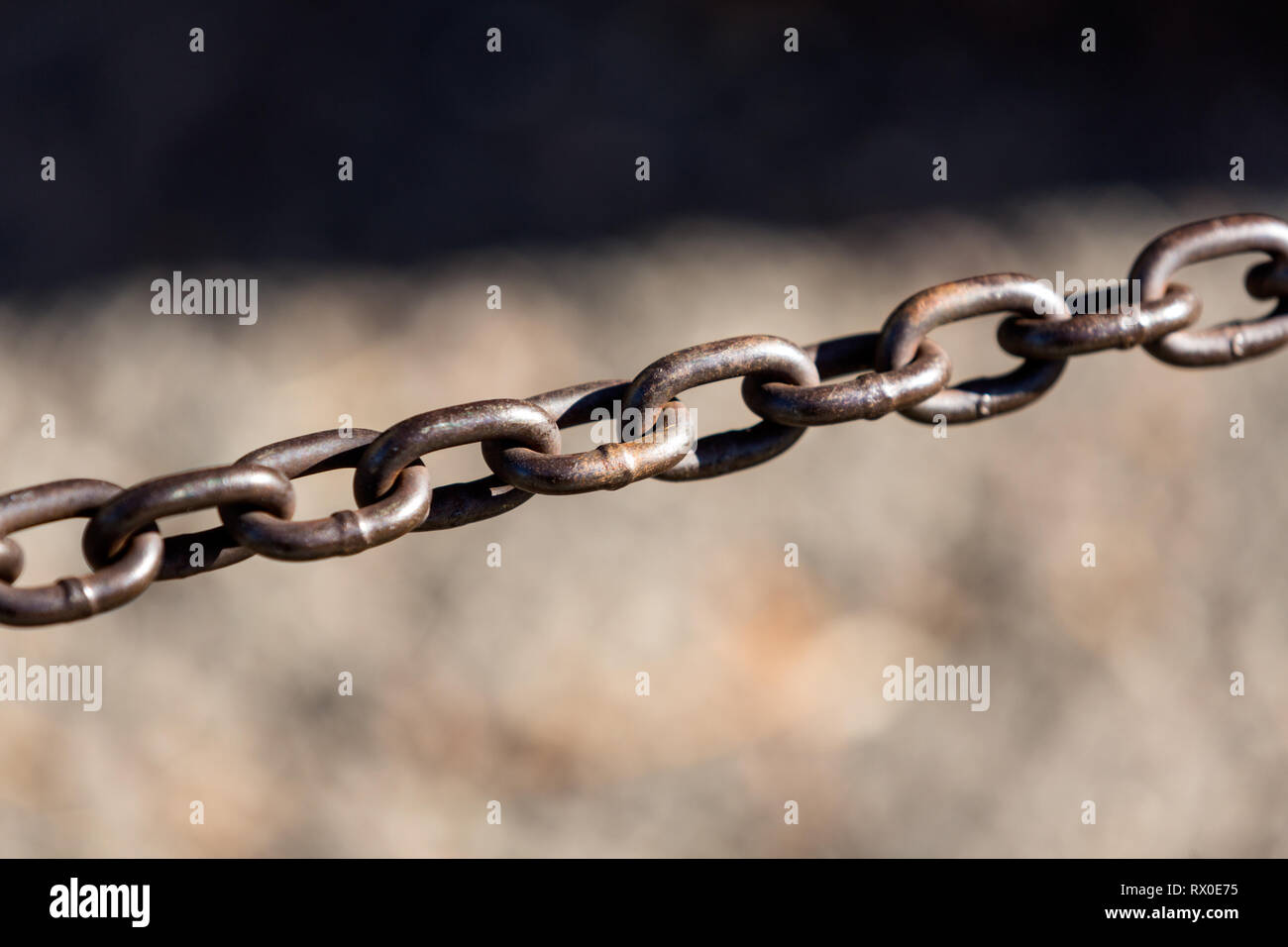 Thick iron chain stretching across a well lit space Stock Photo - Alamy
